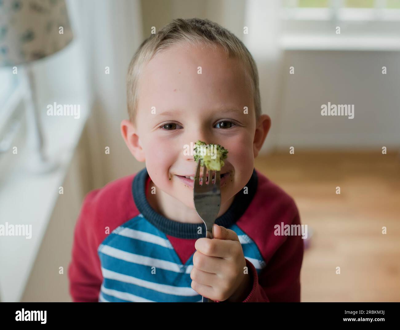 young boy eating broccoli playfully whilst smiling Stock Photo - Alamy
