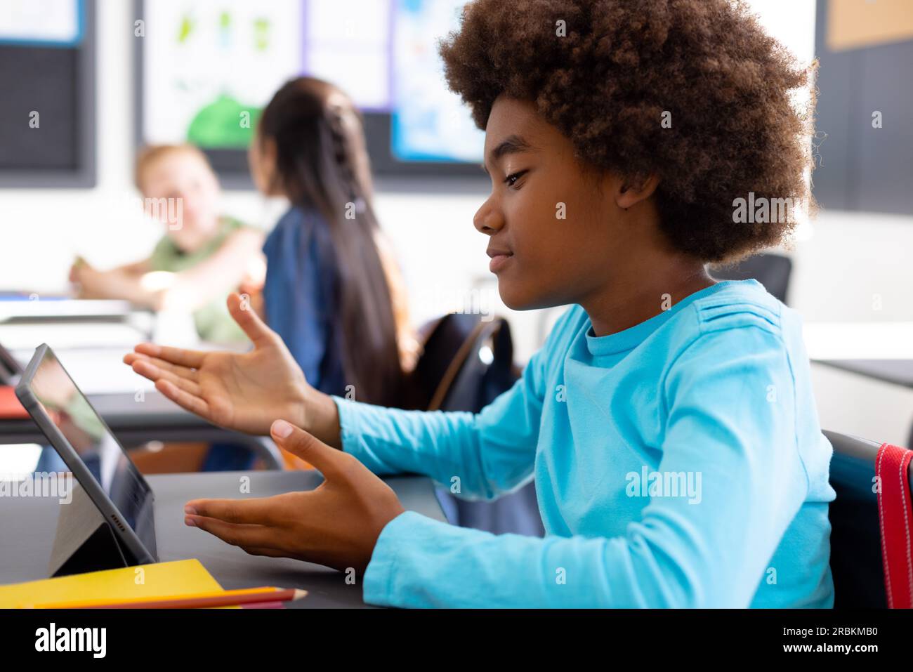 Happy diverse schoolchildren sitting at desks in school classroom Stock ...