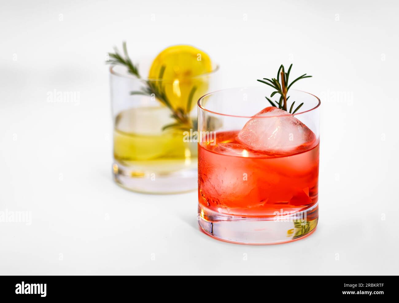 Red cocktail with decoration in a tumbler glass with ice cubes isolated ...