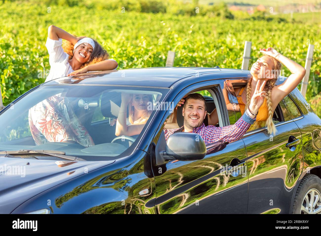 Happy friends waving hands outside open window car during road trip ...