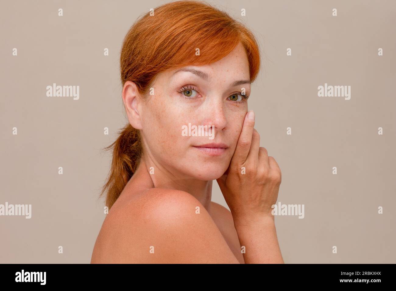 Portrait of cropped caucasian middle aged woman face with freckles holding fingers on cheek ...