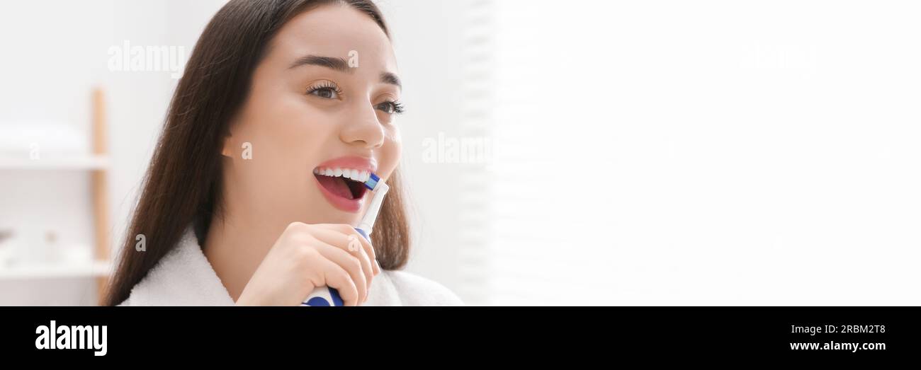 Happy woman using electric toothbrush in bathroom. Banner design with ...
