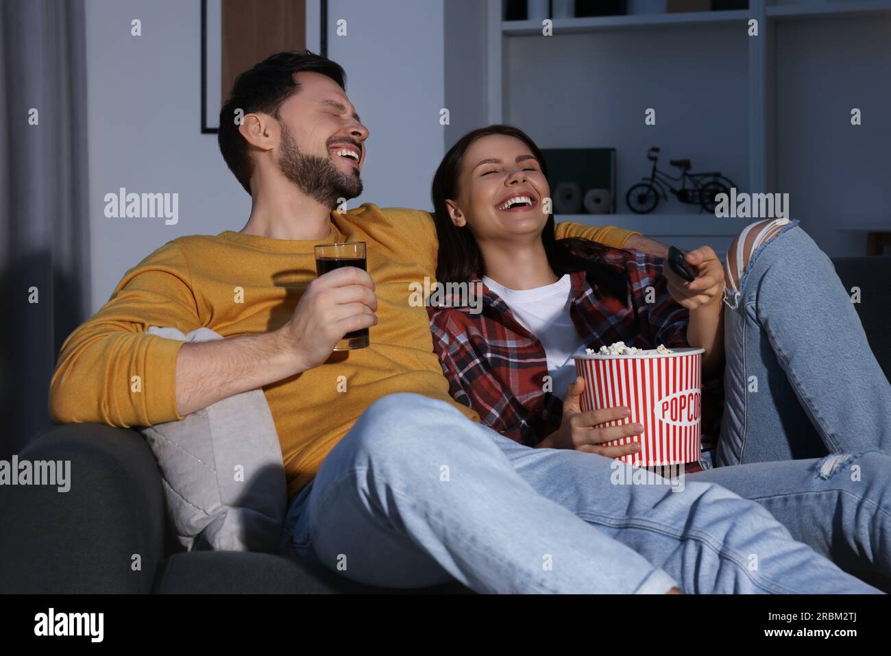 Couple watching comedy via TV and laughing at home in evening Stock ...