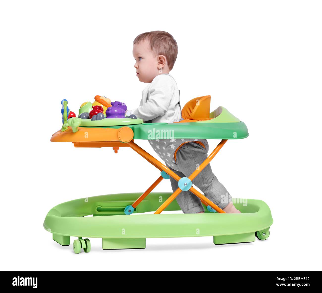 Cute little boy making first steps with baby walker on white background ...