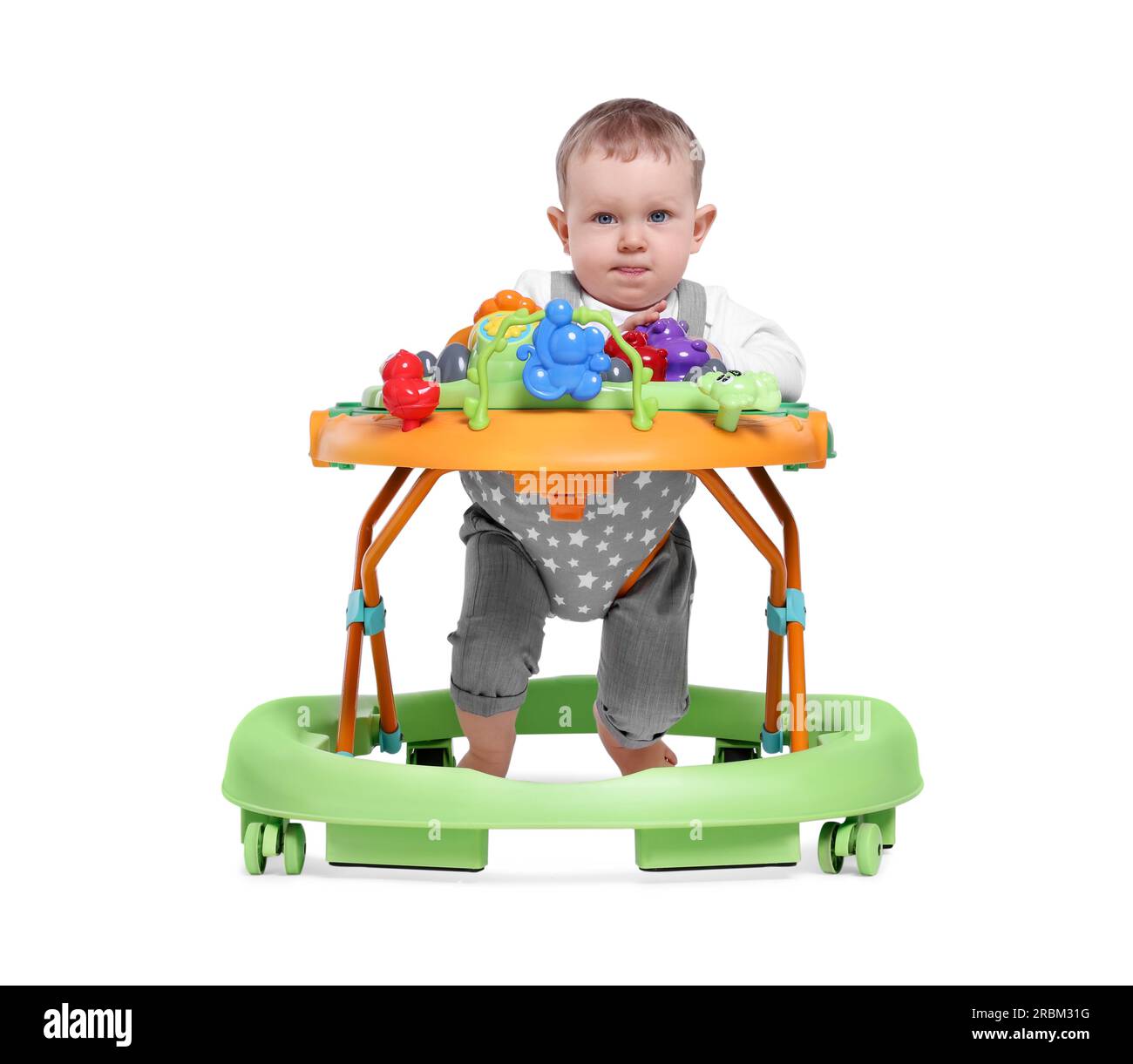 Cute little boy making first steps with baby walker on white background ...