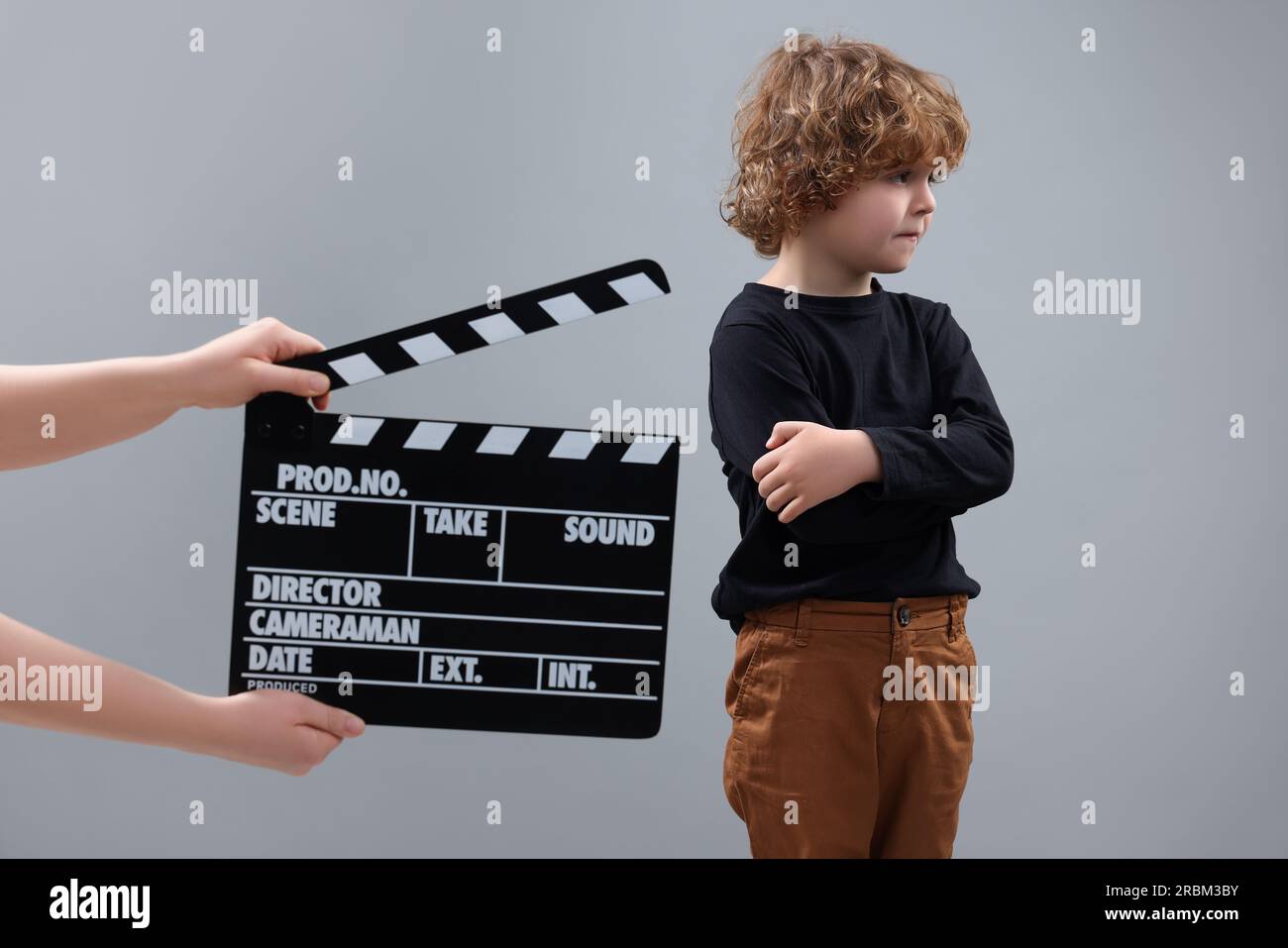 Sad boy performing while second assistant camera holding clapperboard ...