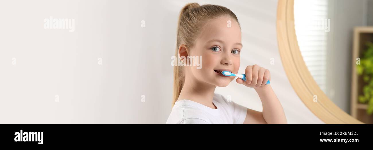 Cute little girl brushing her teeth with plastic toothbrush in bathroom ...