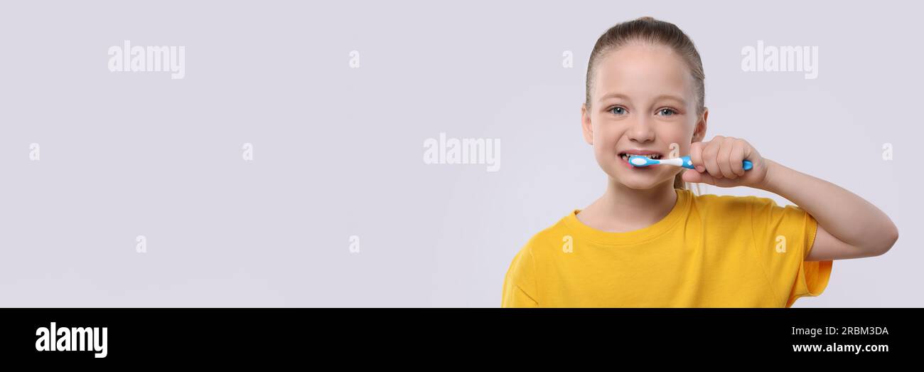 Happy girl brushing her teeth with toothbrush on white background ...