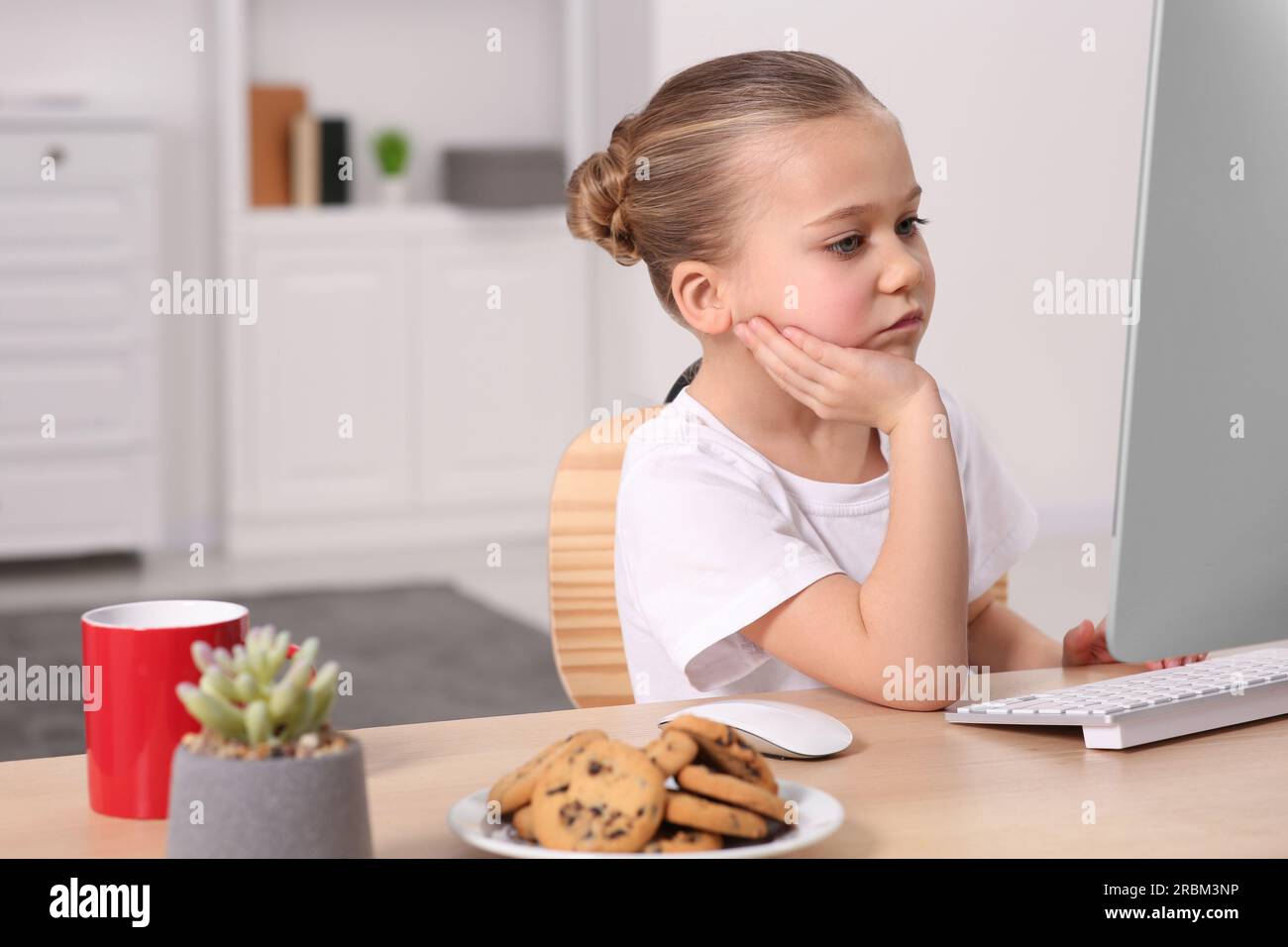 Little girl using computer at table in room. Internet addiction Stock ...