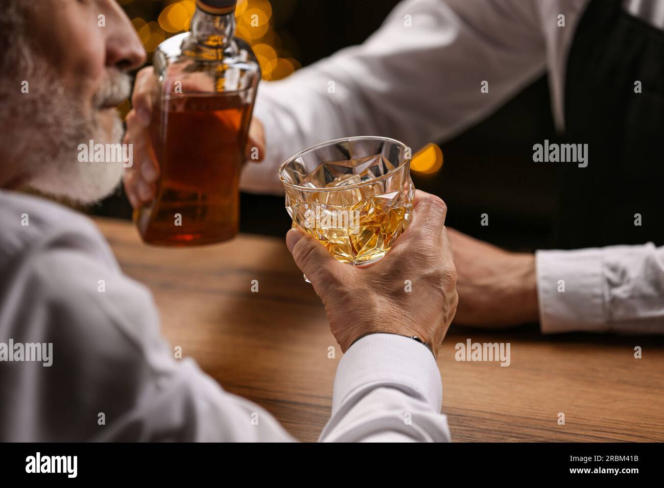 Bartender pouring whiskey in glass for customer at bar counter, closeup ...