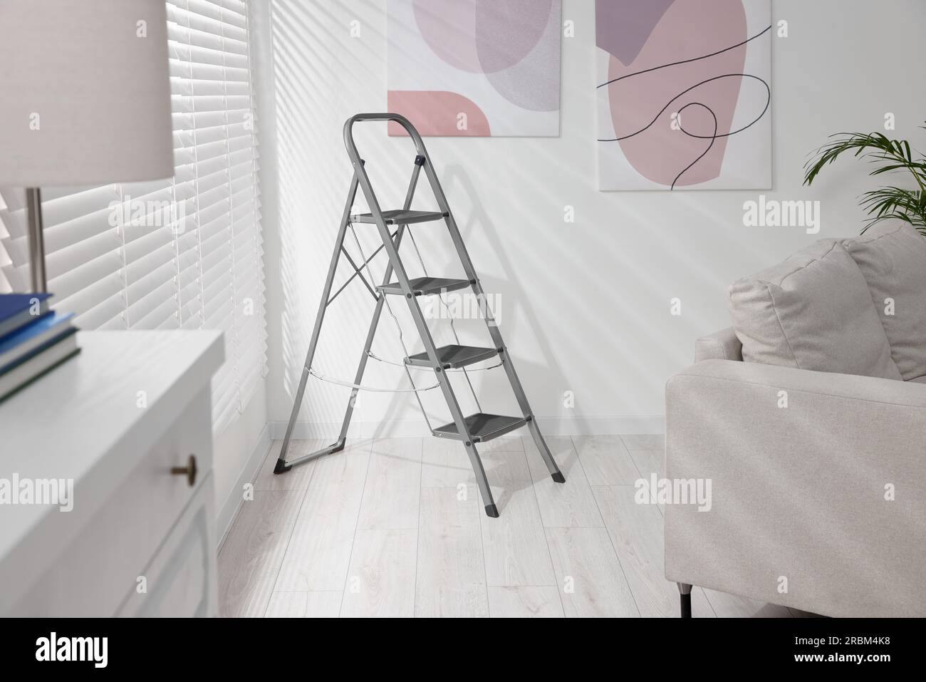 Metal ladder near window and abstract pictures in living room Stock ...