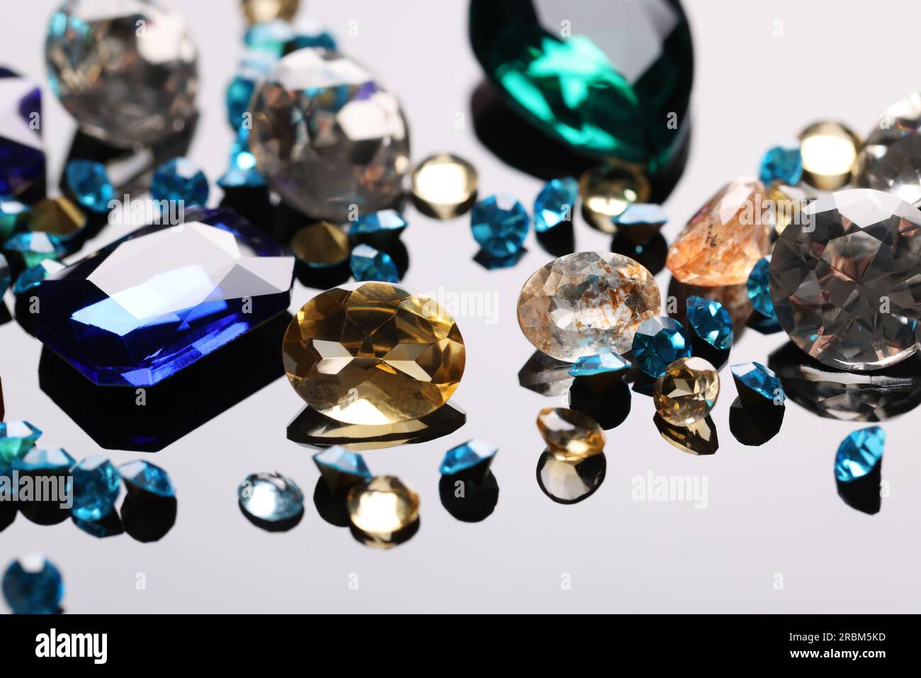 Different beautiful gemstones for jewelry on mirror surface Stock Photo ...