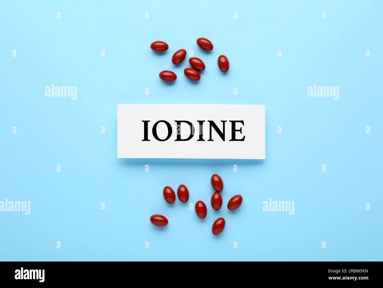 Card with word Iodine and pills on light blue background, flat lay ...