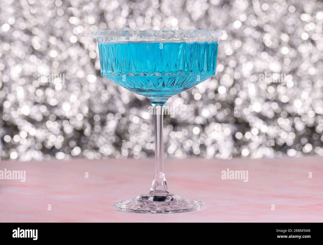 Glass of refreshing light blue drink on pink marble table against ...