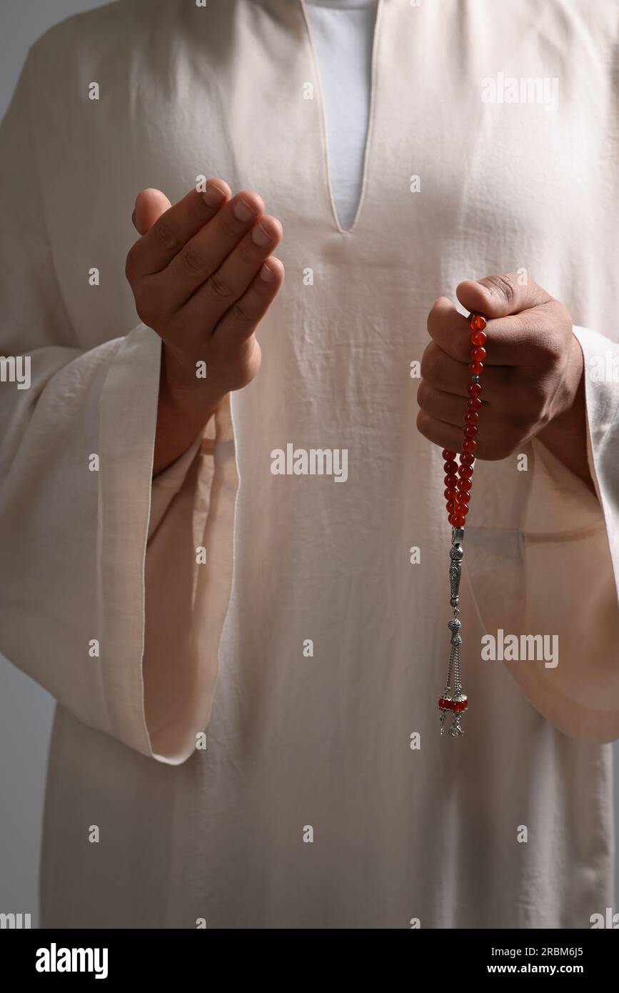 Muslim man with misbaha praying on light grey background, closeup Stock ...