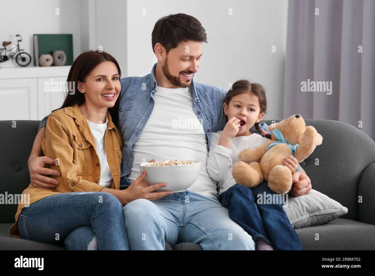 Happy family spending time together while watching TV at home Stock ...
