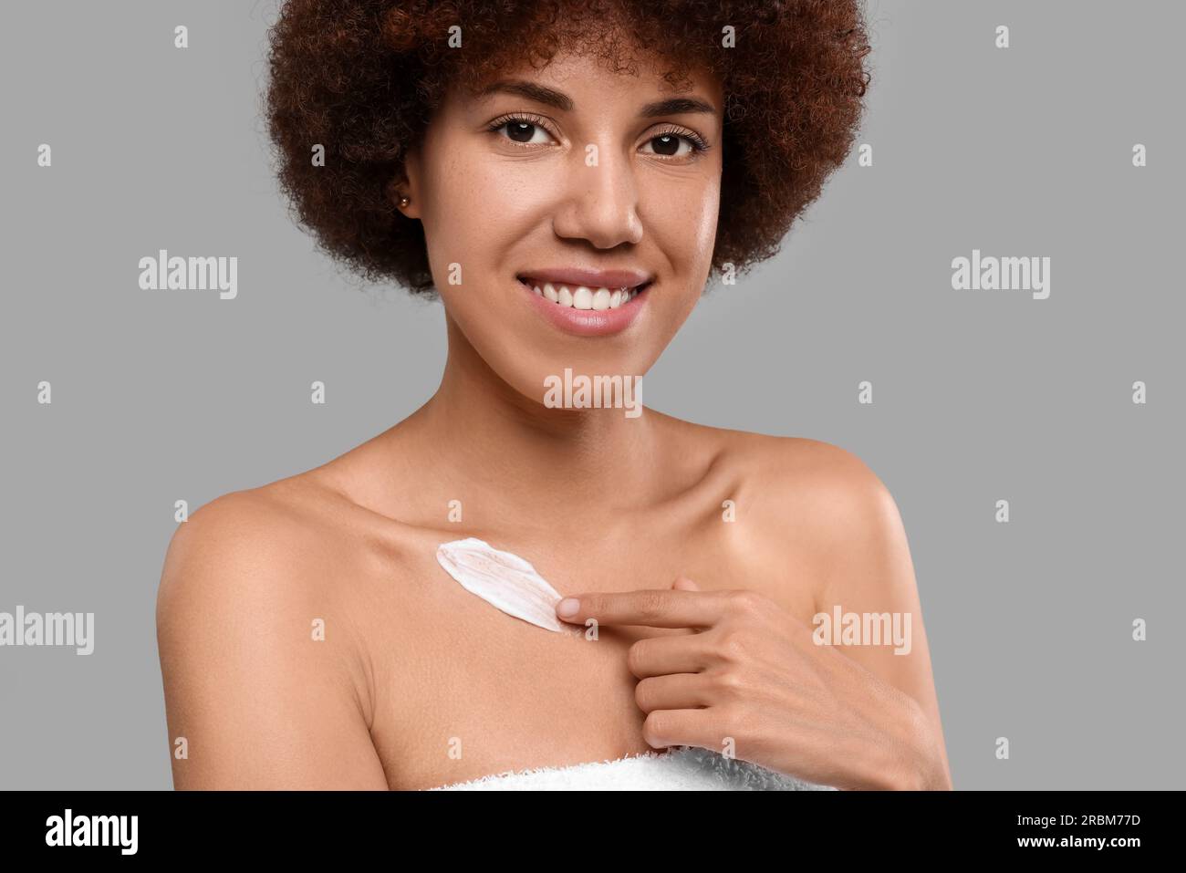 Beautiful young woman applying cream onto body on grey background Stock ...