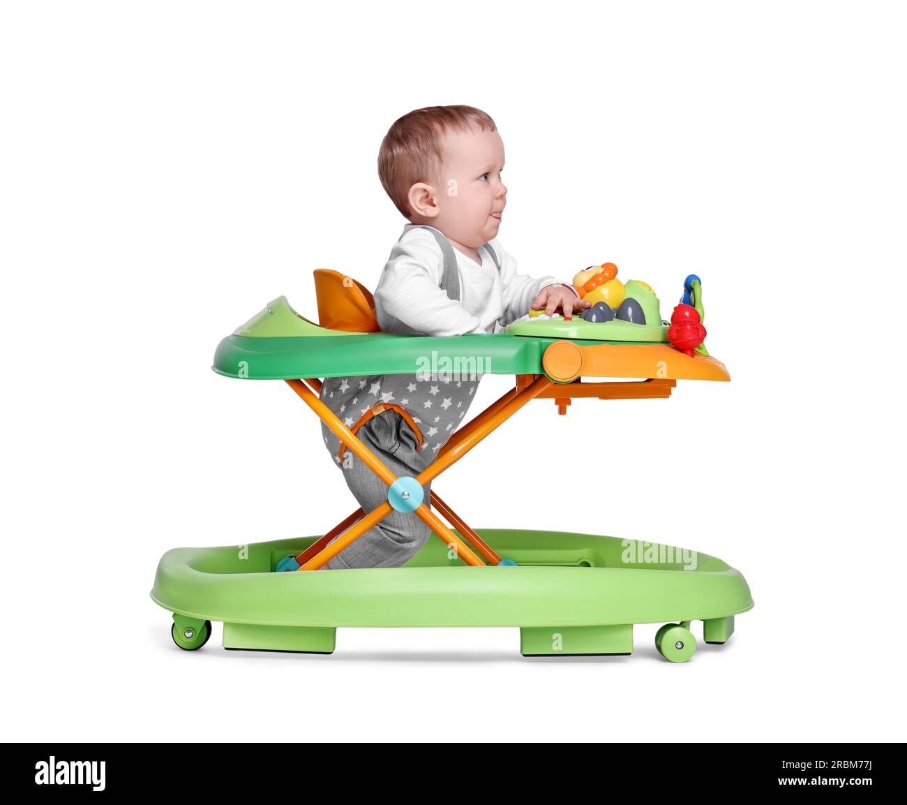 Cute little boy making first steps with baby walker on white background ...
