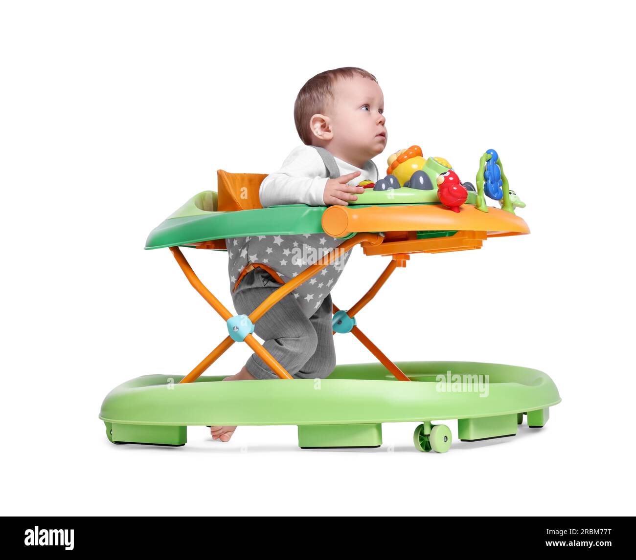 Cute little boy making first steps with baby walker on white background ...