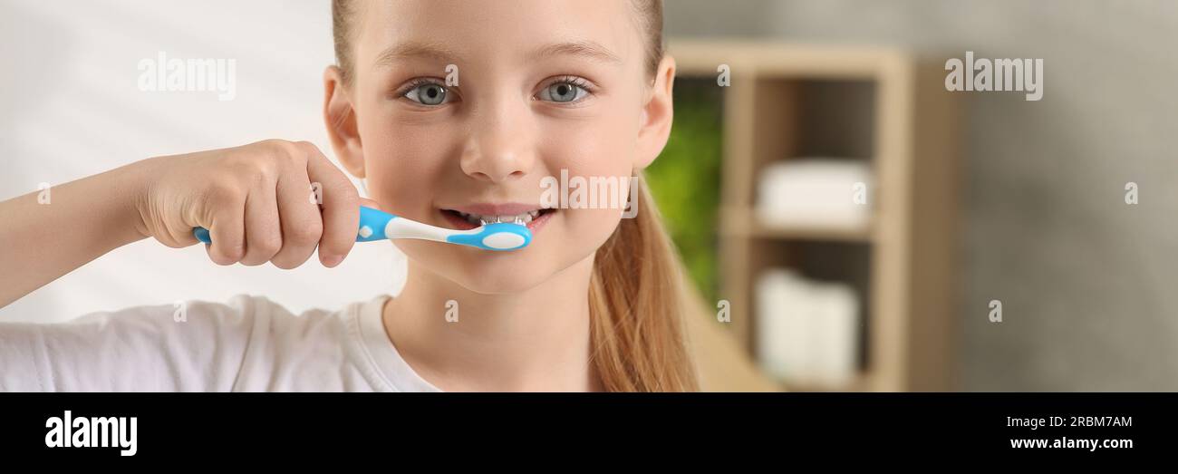 Cute little girl brushing her teeth with plastic toothbrush in bathroom ...