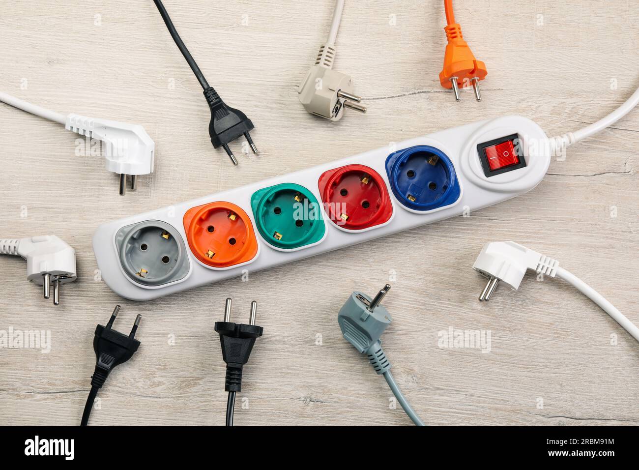 Power strip with extension cord on white wooden floor, flat lay ...