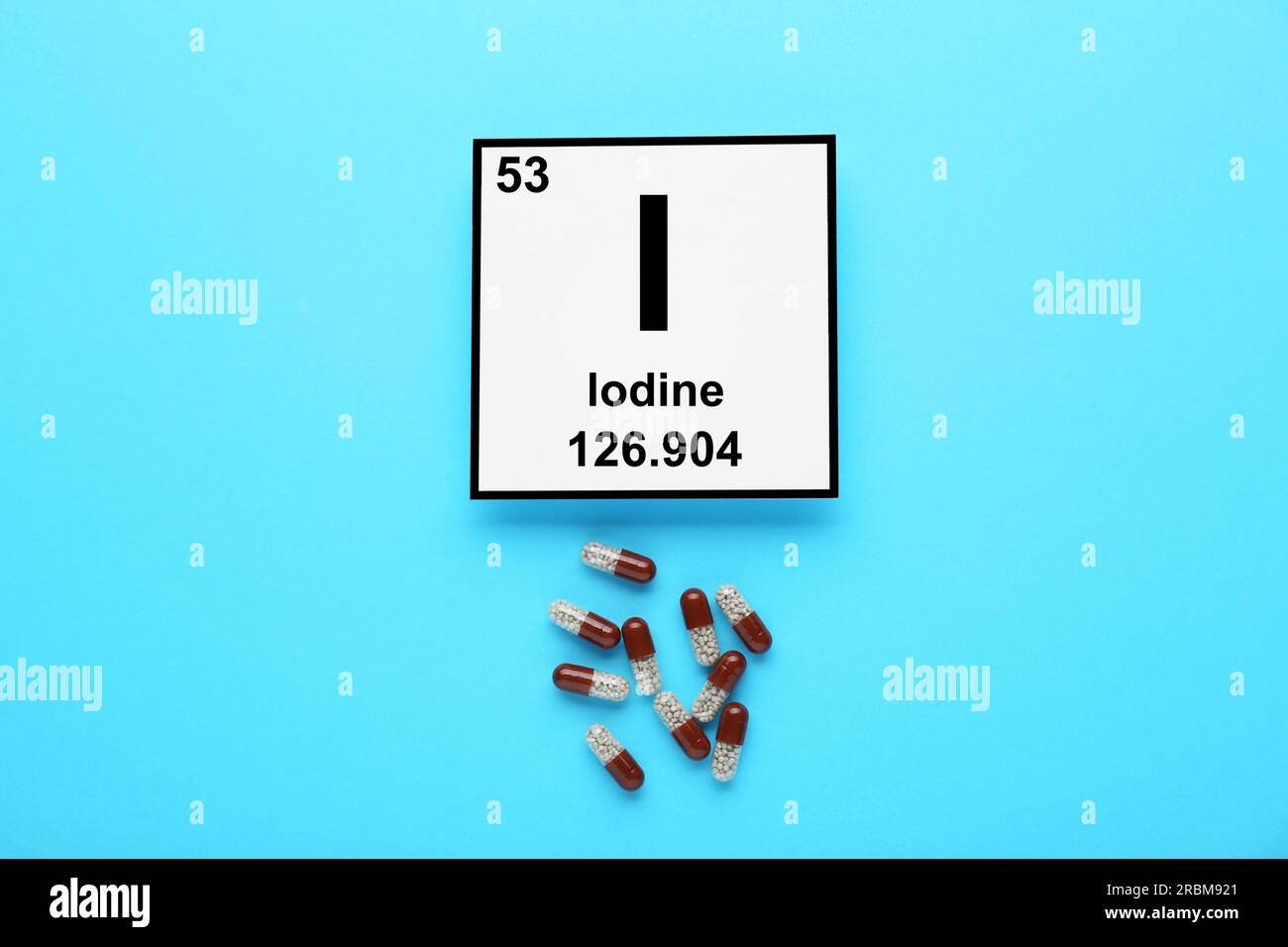 Card with iodine element and pills on light blue background, flat lay ...