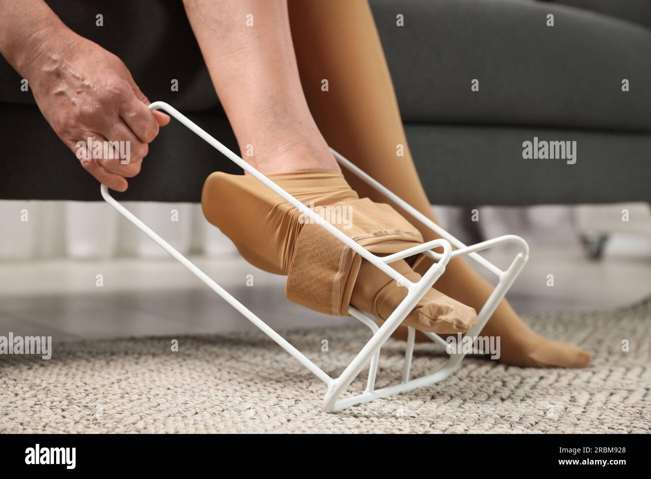 Woman putting on compression tights with stocking donner in living room ...