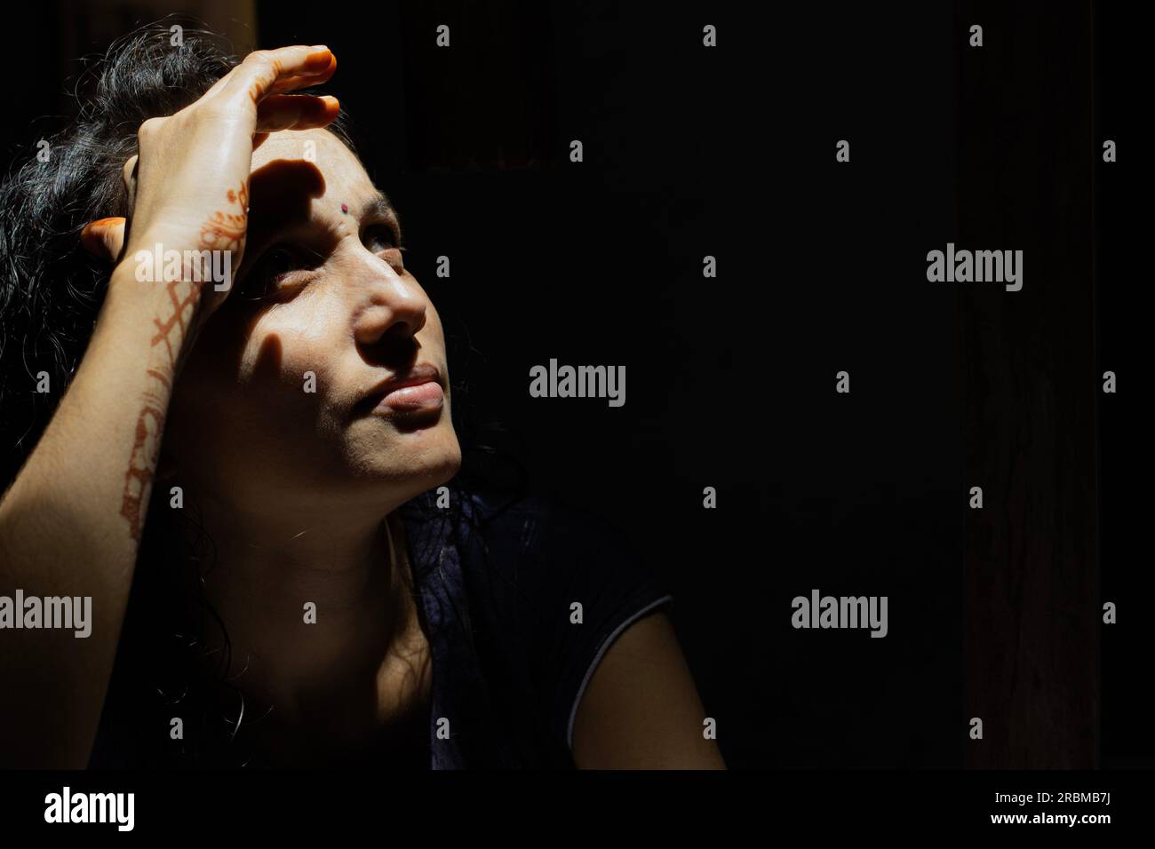 Beautiful Indian model with dramatic dark light and shadow looking up ...
