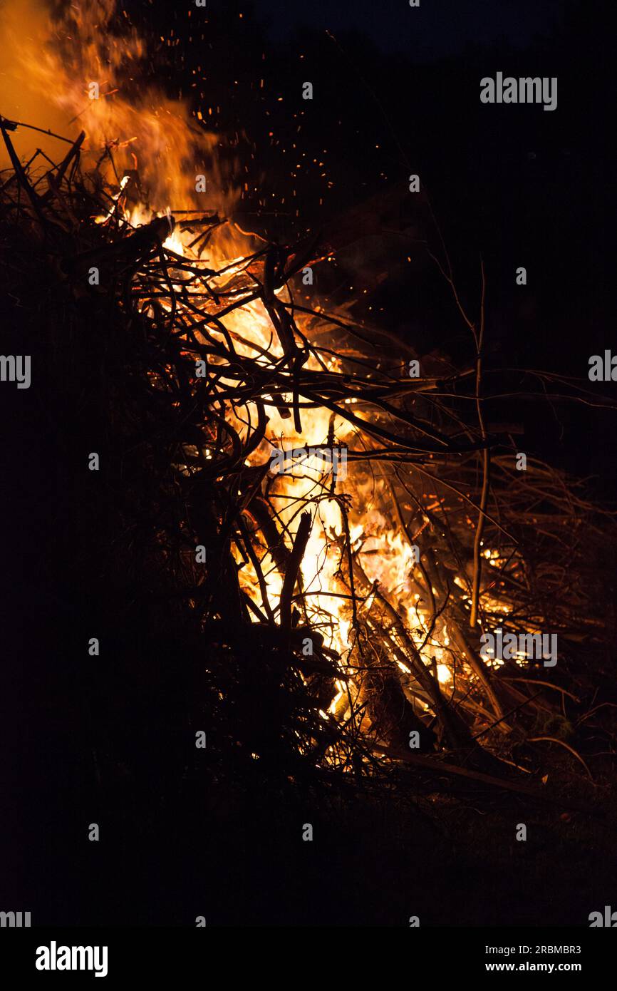 The side of a bonfire burns with an intensity, sending flames and ...