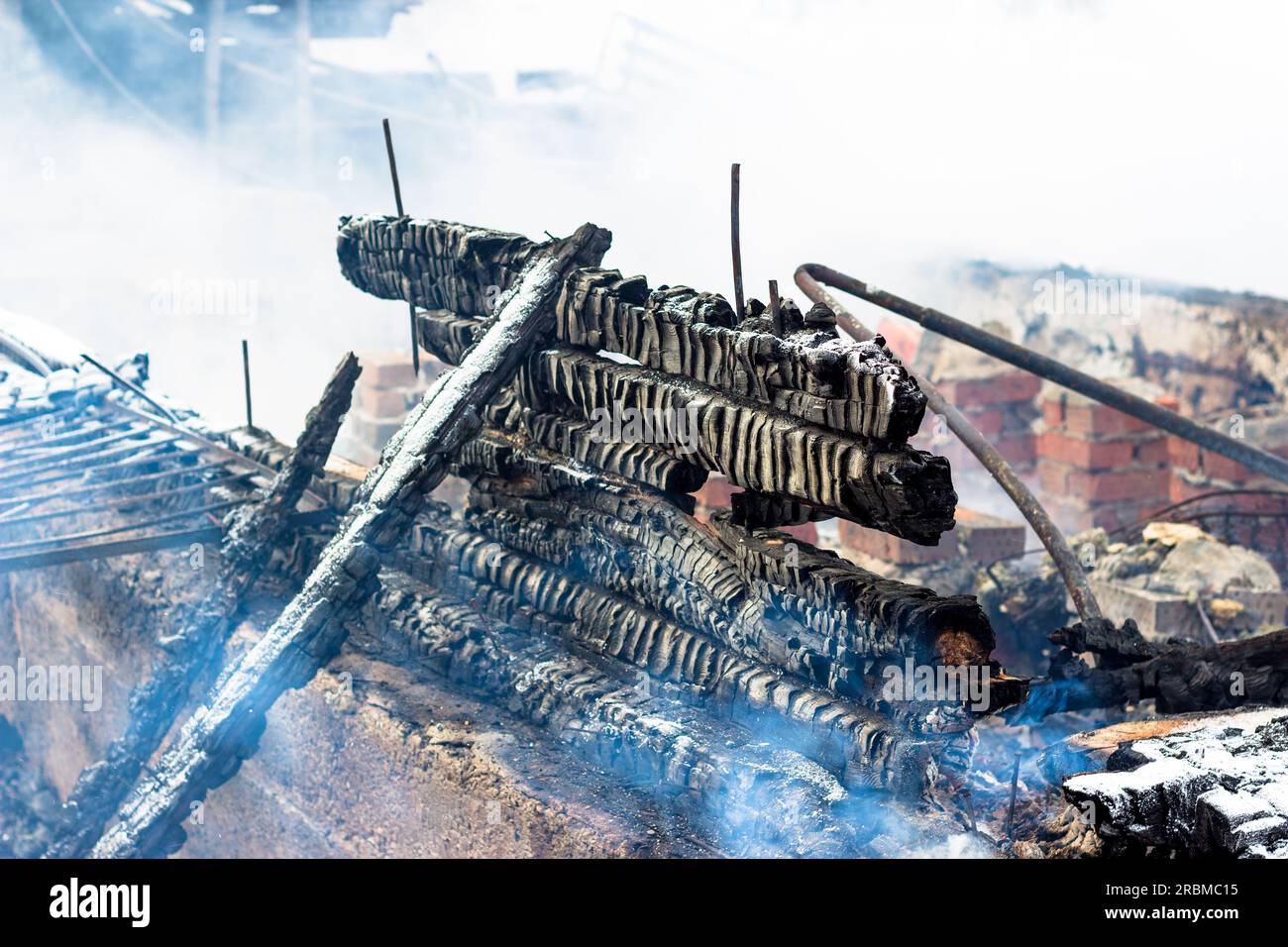 Charred planks and smoke on the ashes, burnt walls of a wooden house ...