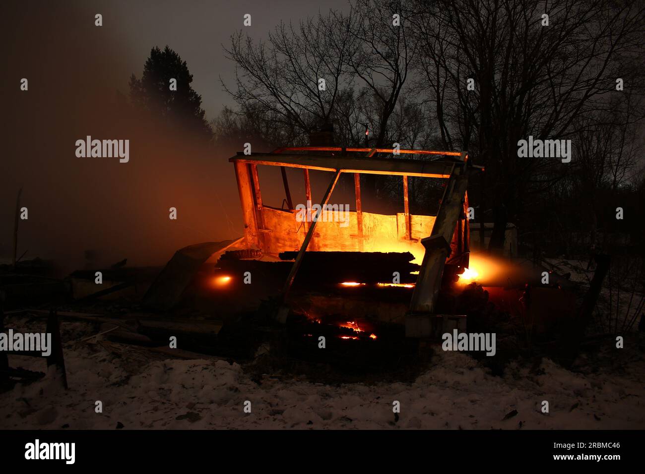 Fire in the private sector. Burning building, night view. Burning out remains of a wooden house ...