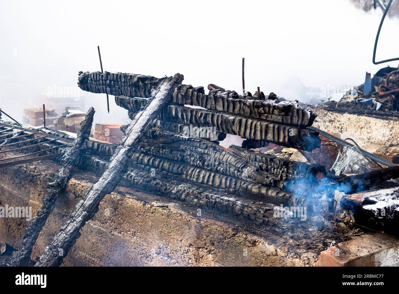 Burnt walls of a wooden house after a fire. Charred planks and smoke on ...