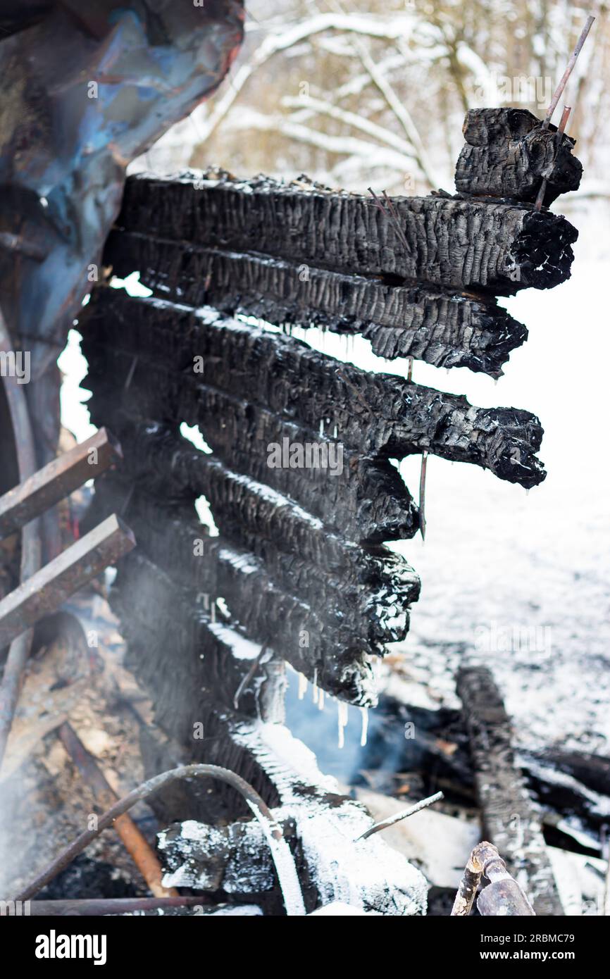 Burnt walls of a wooden house after a fire. Charred planks and smoke on ...