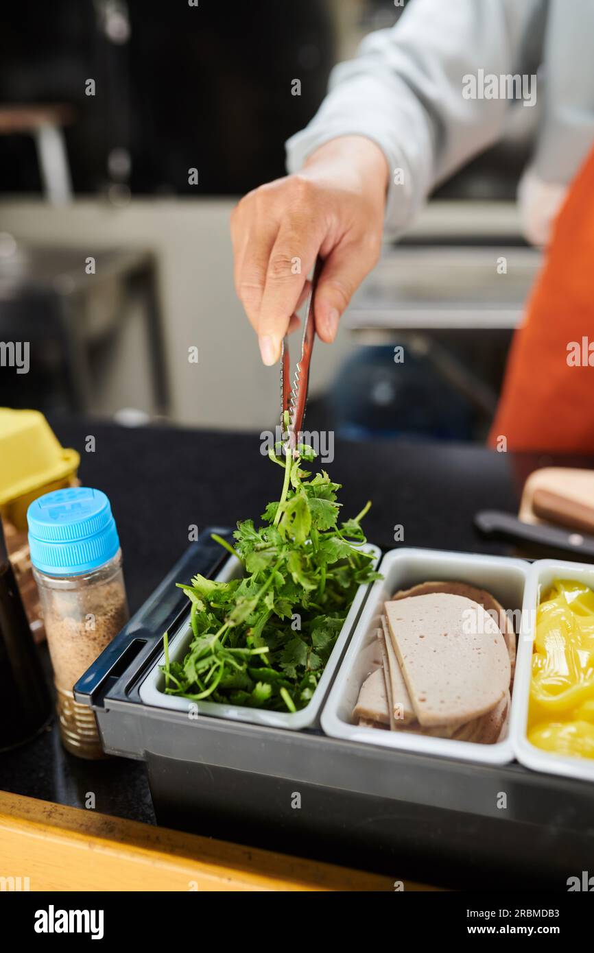 Closeup image of cook adding cilantro in sandwich for customer Stock ...