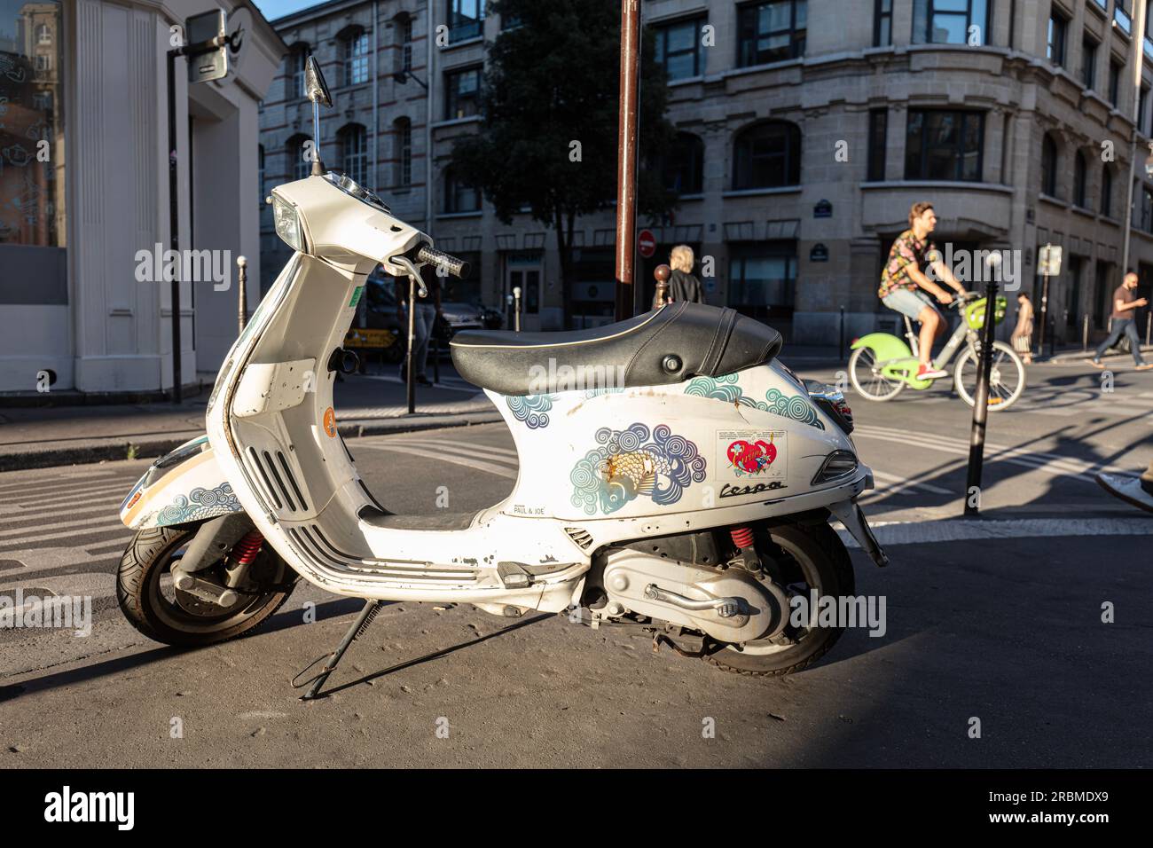 Vespa scooter in city centre with person riding bicycle in background ...