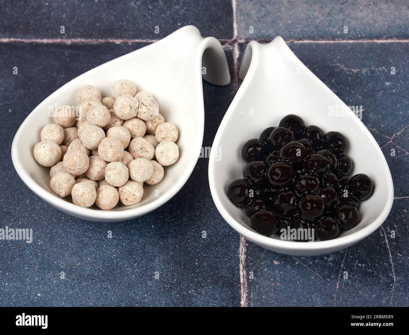 Raw and cooked tapioca balls with different flavors, also known as boba in bubble tea, on gray ...