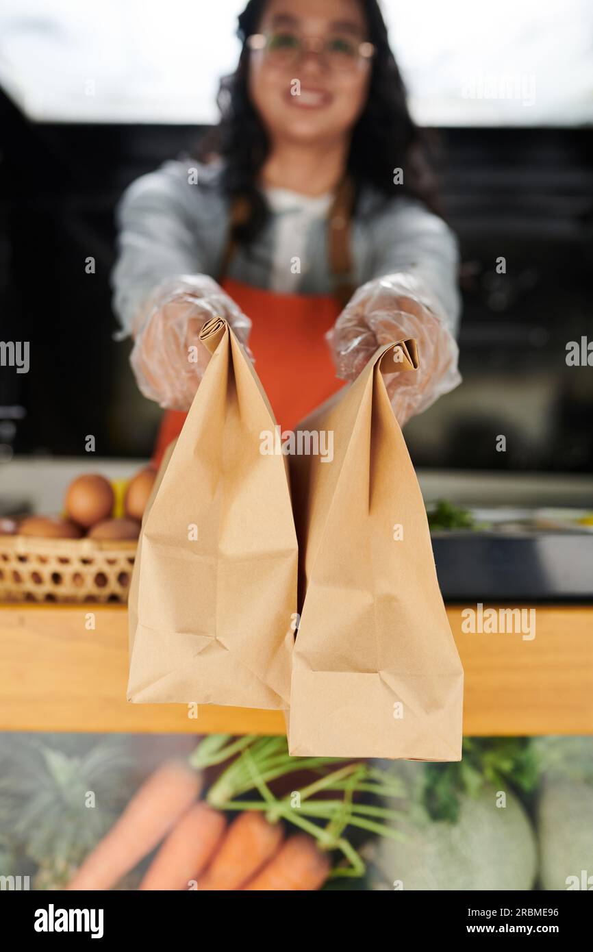 Food truck worker giving paper packages with cooked order Stock Photo ...