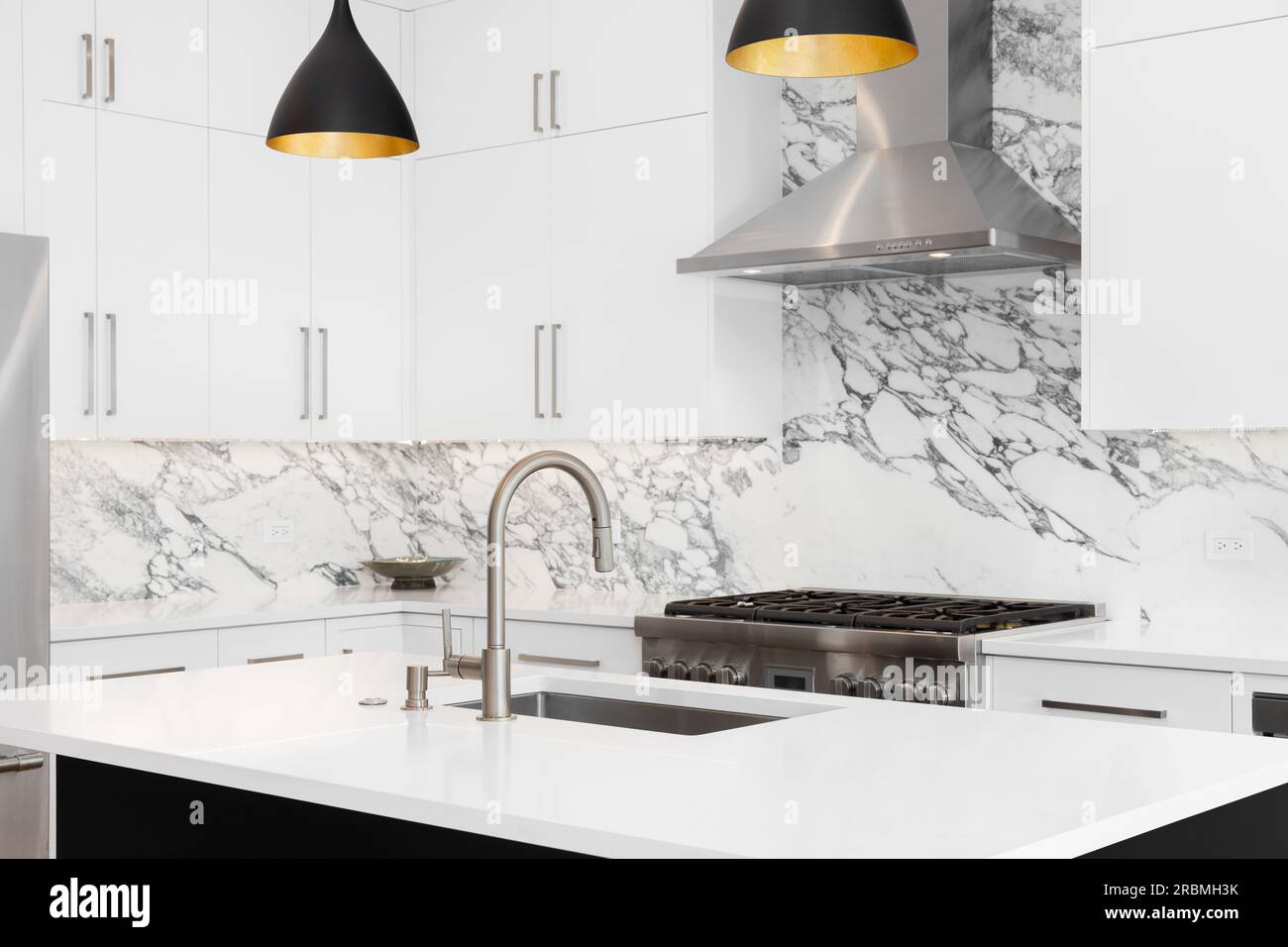 A kitchen detail with white cabinets, modern light fixtures hanging ...