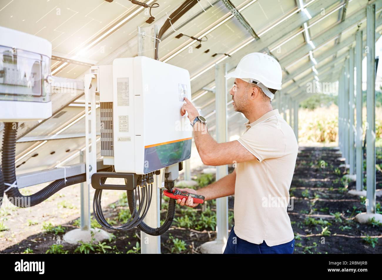 Professional worker checking voltage on solar inverter. Male using ...