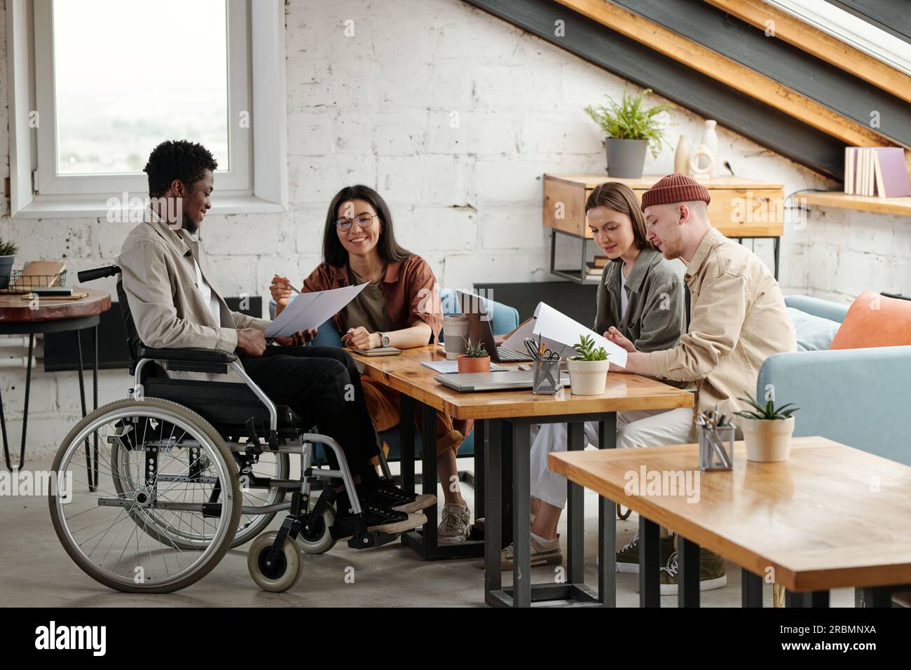 Two pairs of employees working in small groups by workplace while ...