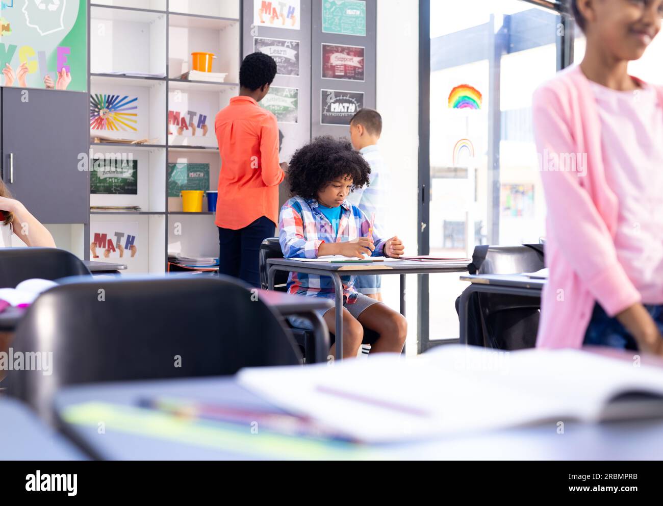 Diverse female teacher and school pupils working in classroom with copy ...
