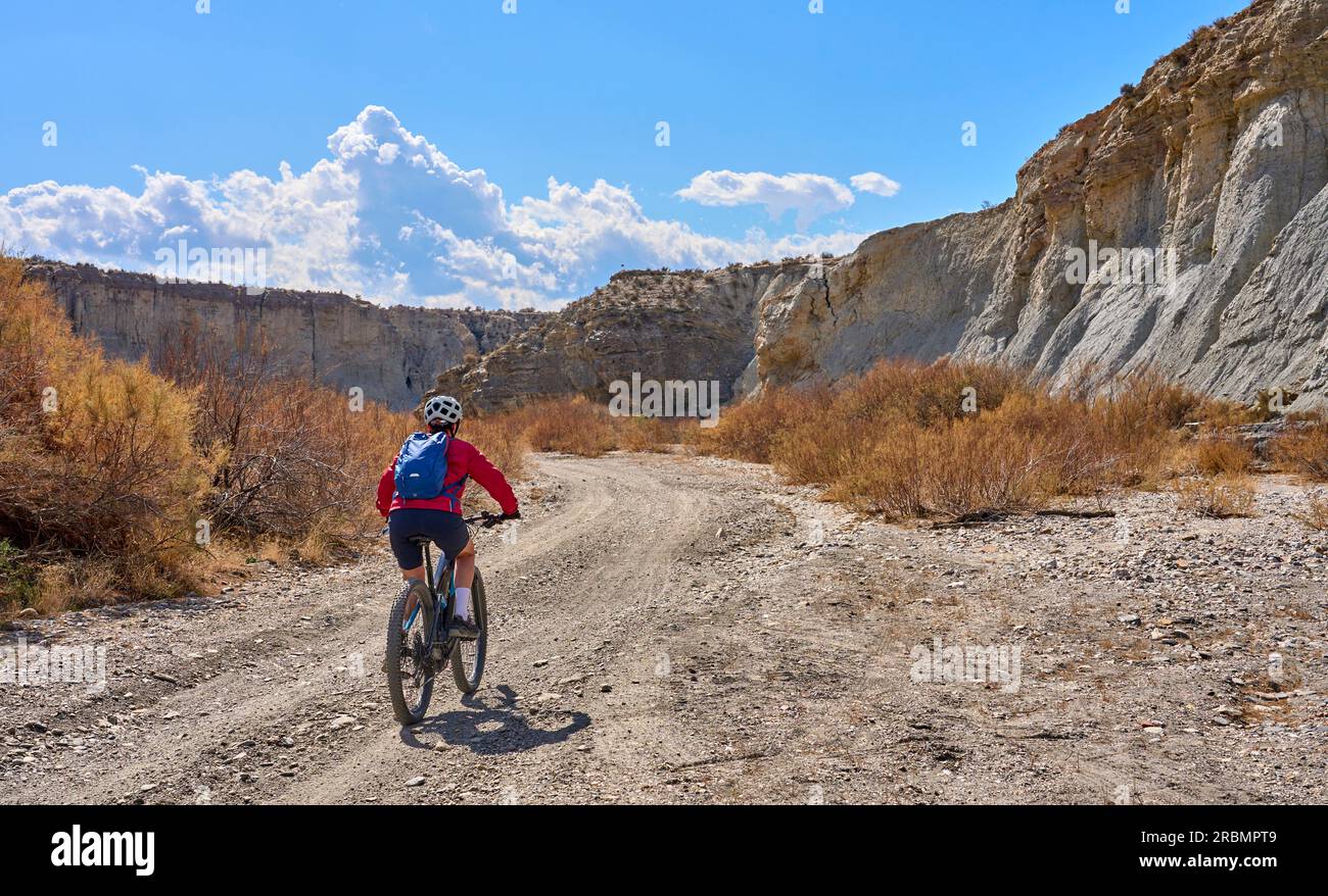 nice, active senior woman with her electric mountain bike on a trail tour in the desert of ...