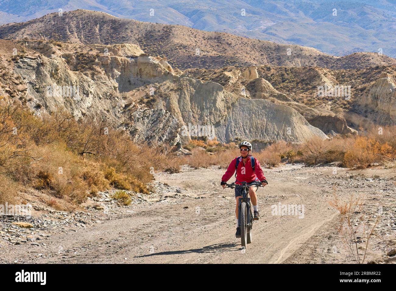nice, active senior woman with her electric mountain bike on a trail ...