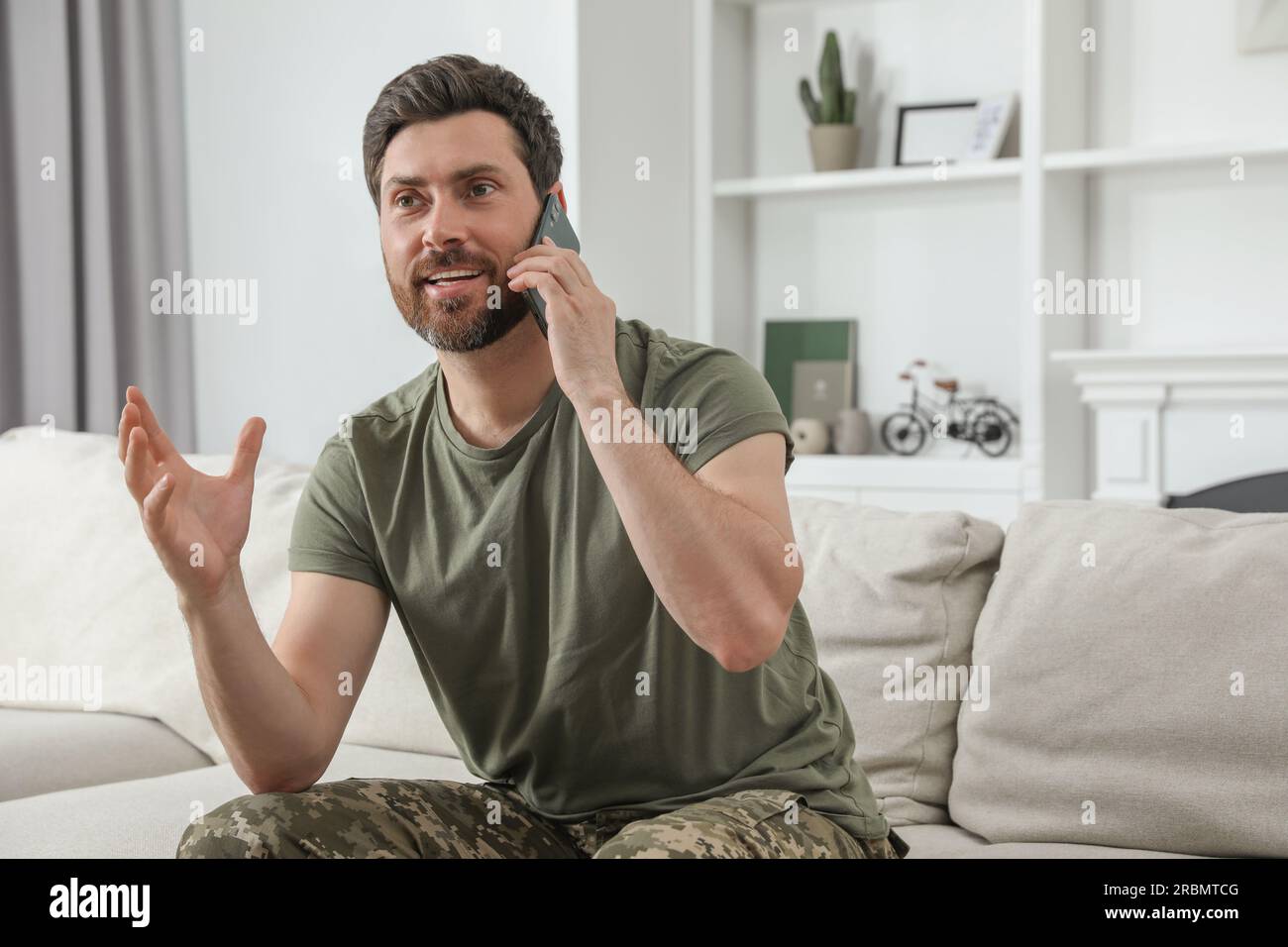 Happy soldier talking on phone in living room. Military service Stock ...