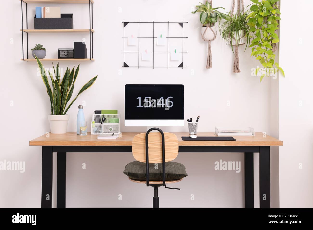Cozy workplace with computer, modern furniture and houseplants at home ...