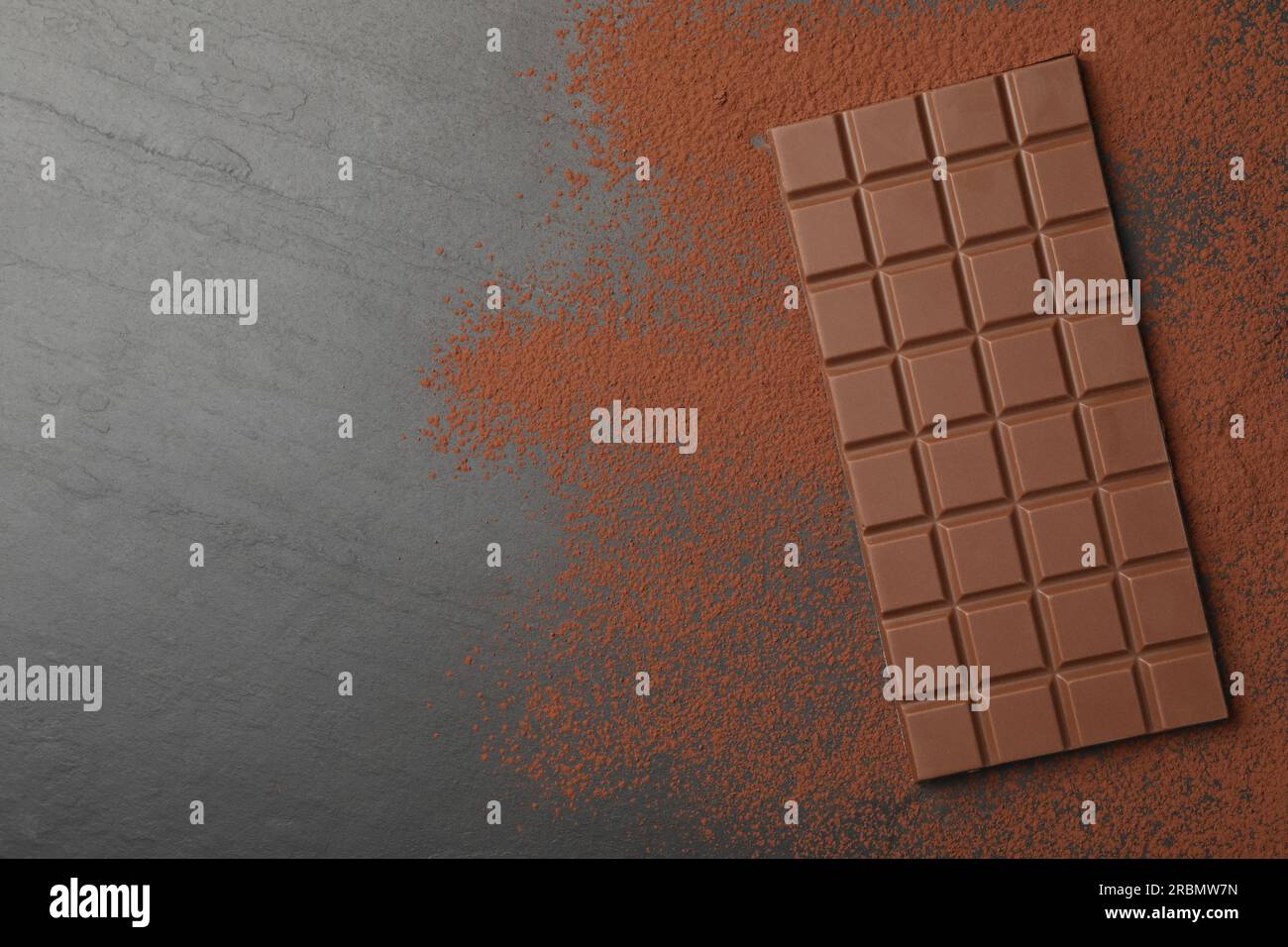 Tasty chocolate bar and cocoa powder on grey table, top view. Space for ...