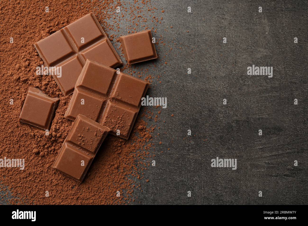 Delicious milk chocolate and cocoa powder on grey table, flat lay ...