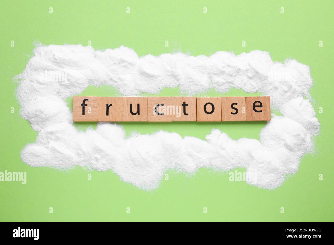 Word Fructose made of wooden cubes and powder on light green background ...