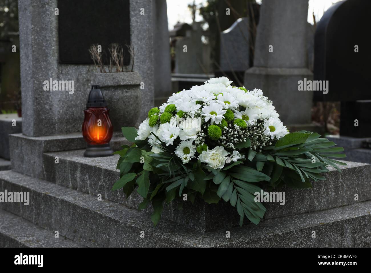 Funeral wreath of flowers and grave lantern on granite tombstone in cemetery Stock Photo - Alamy