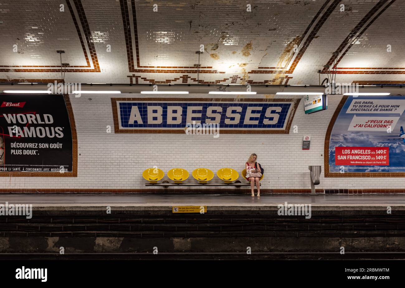 Woman checks mobile phone while waiting for train in Abbesses Metro ...